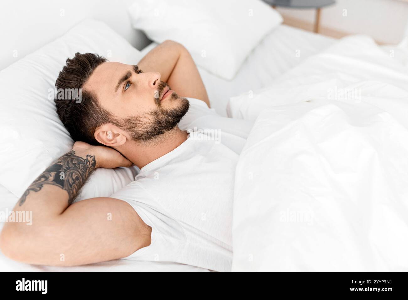 Thoughts in head not let fall asleep. Millennial man lying in bed and ...