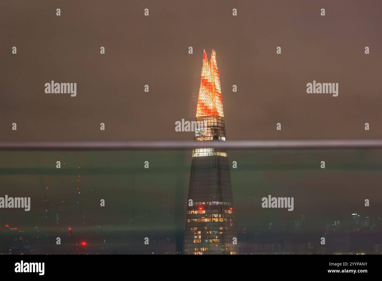 The Shard in London is lit with red and white lights against a cloudy ...