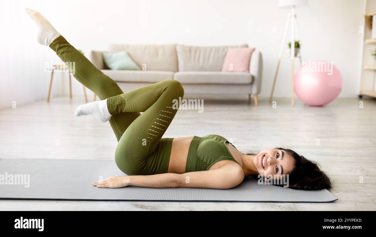 Full length of athletic Indian woman doing abs exercises during her ...