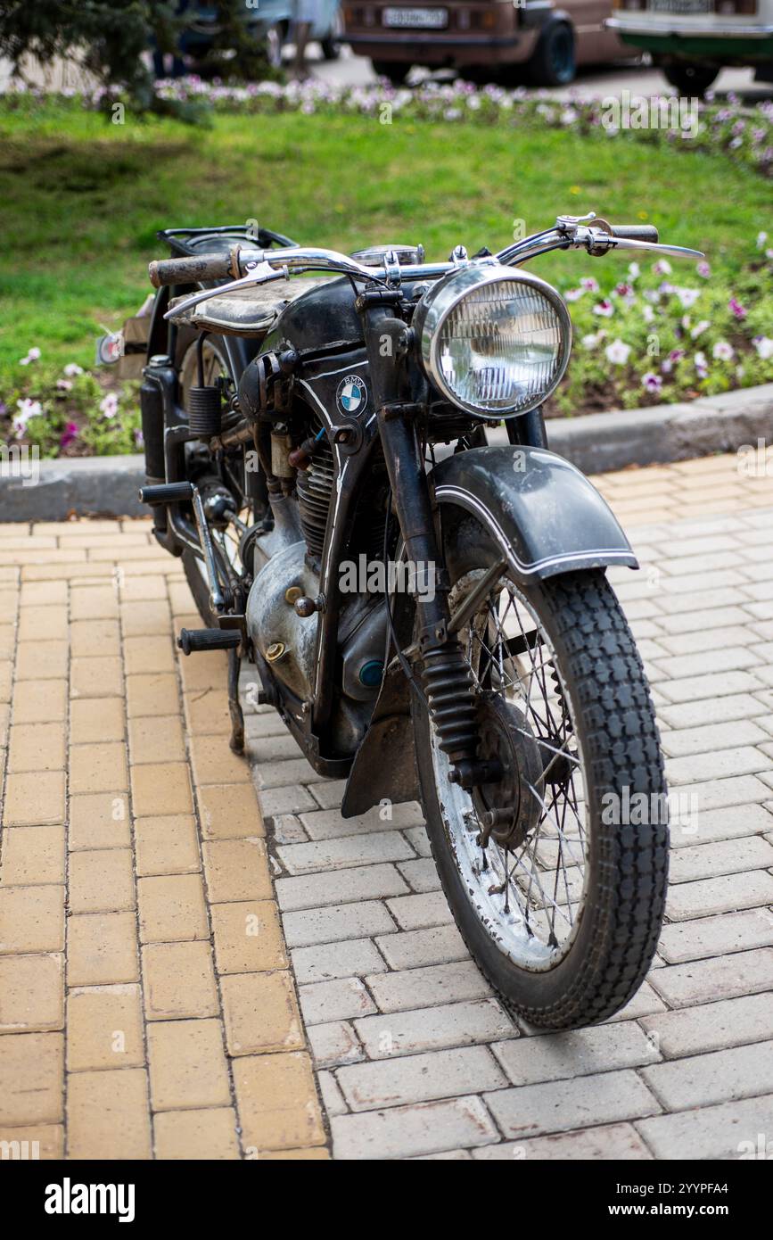 A retro BMW R35 motorcycle stands on the paving stones in the park ...