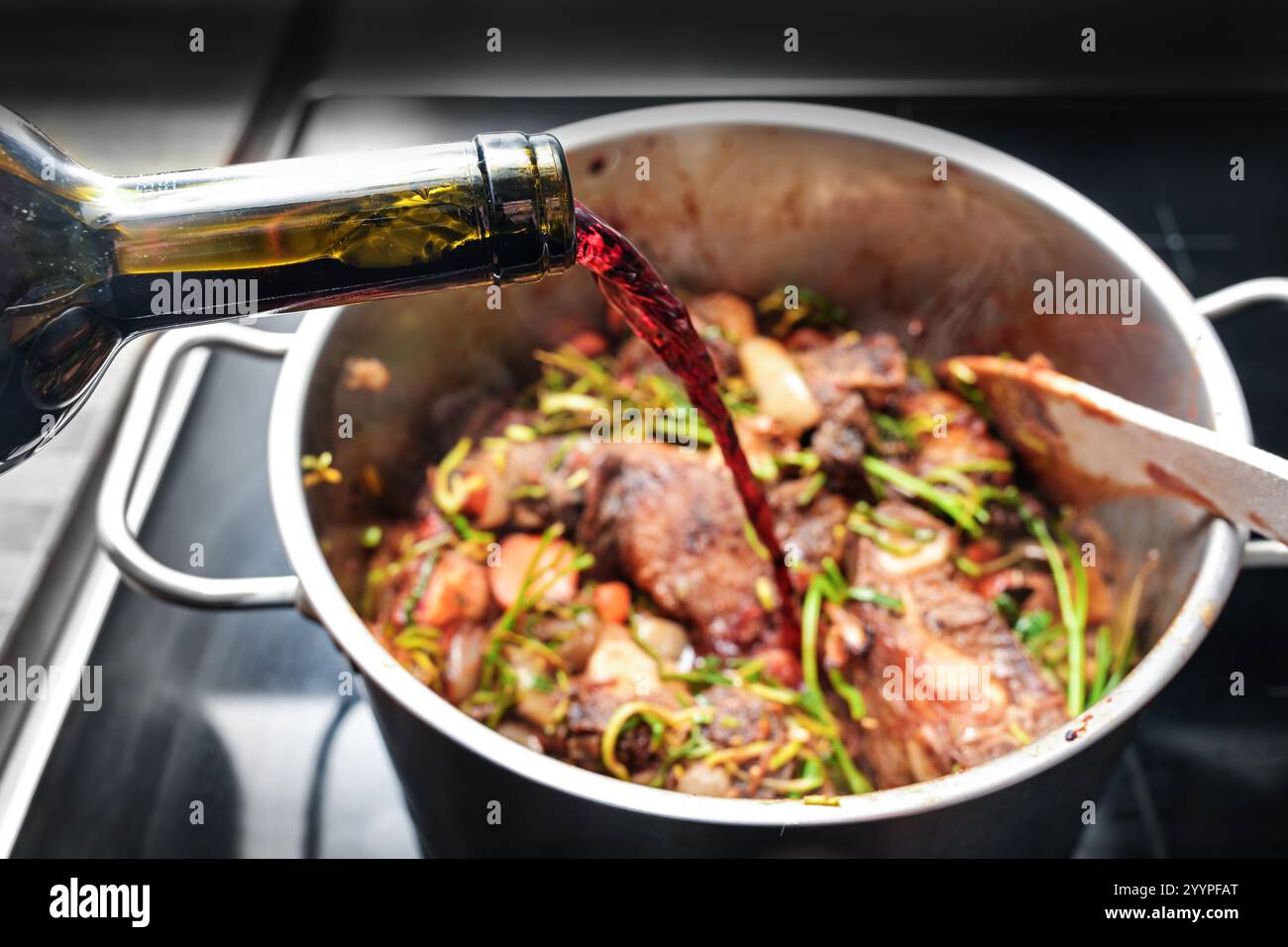 Pouring red wine into a stainless steel pot to deglaze the roasted ...