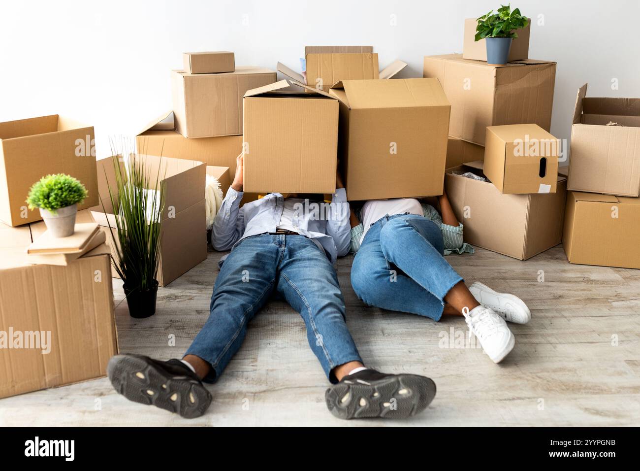 Moving day. Tired african american couple with cardboard boxes on heads ...