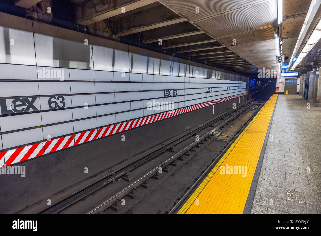 Lex 63 subway station platform in New York City featuring clean tiled walls, bright yellow ...