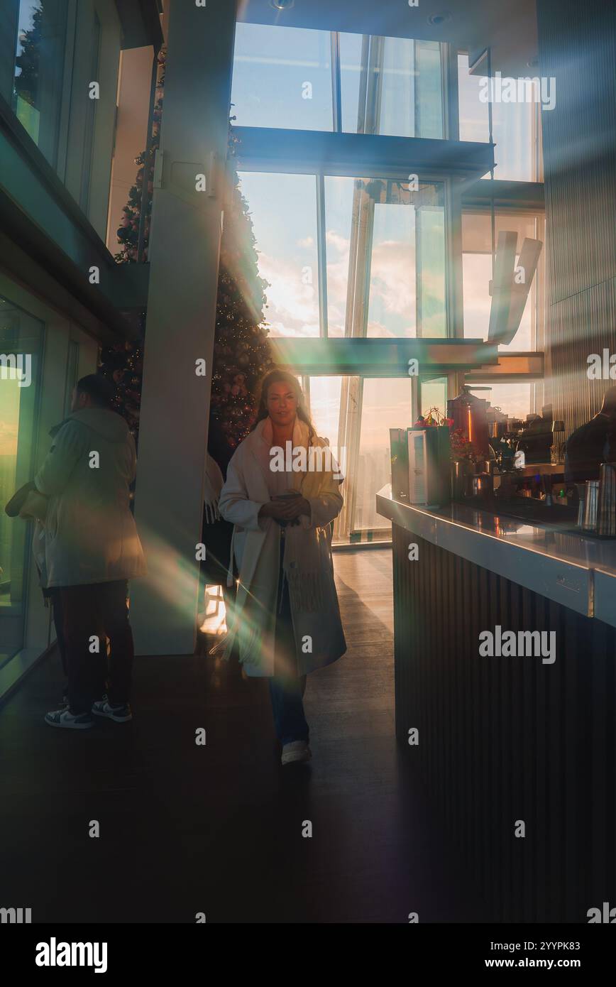 A person in a light coat walks through a modern London interior with ...
