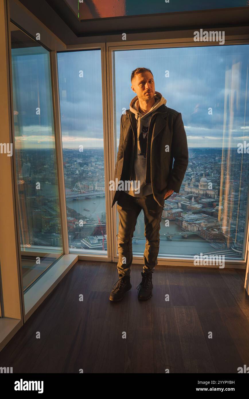 A person stands inside a skyscraper with large windows, overlooking ...