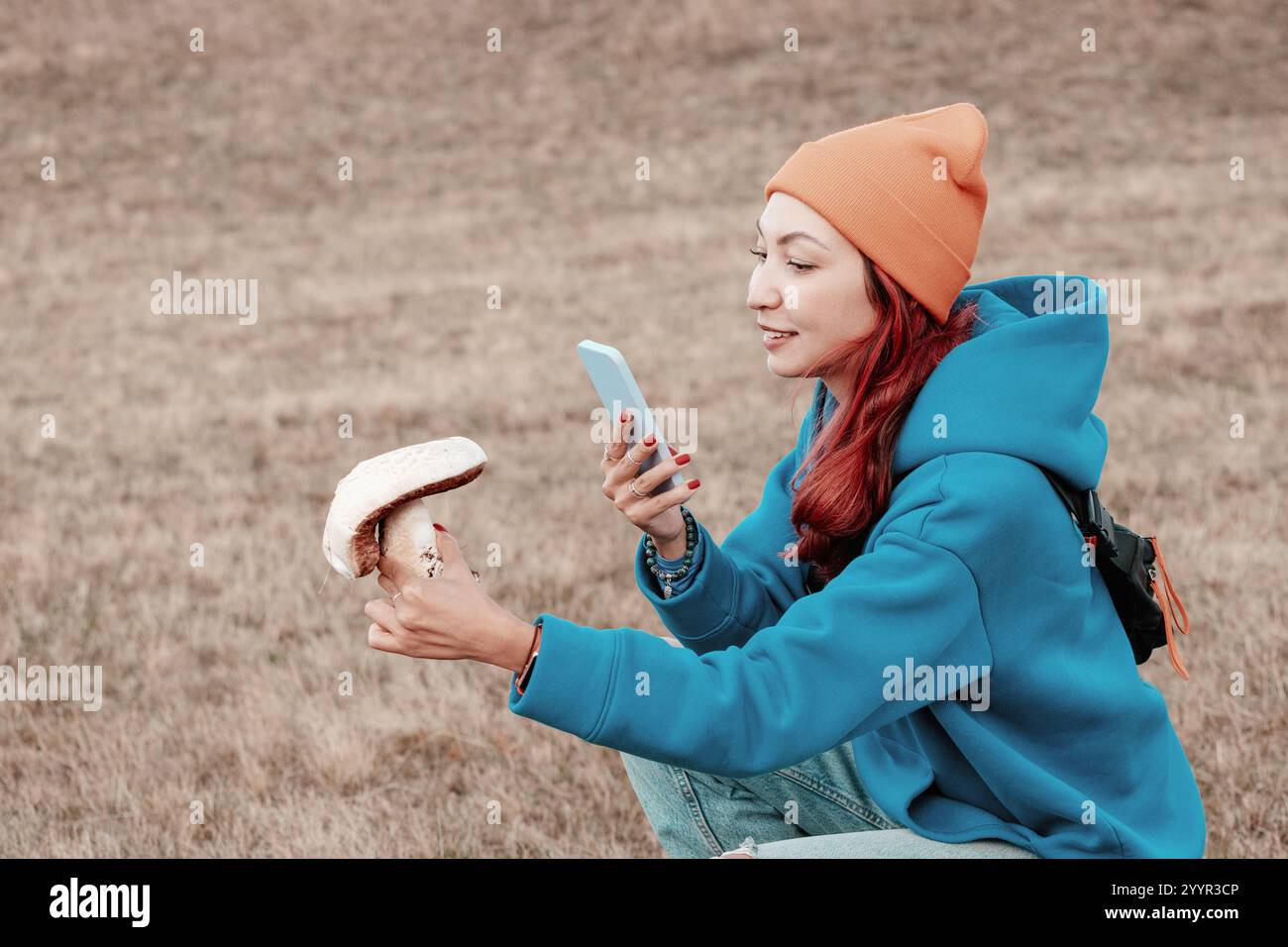 Female mycologist photographing a mushroom using a smartphone in a ...