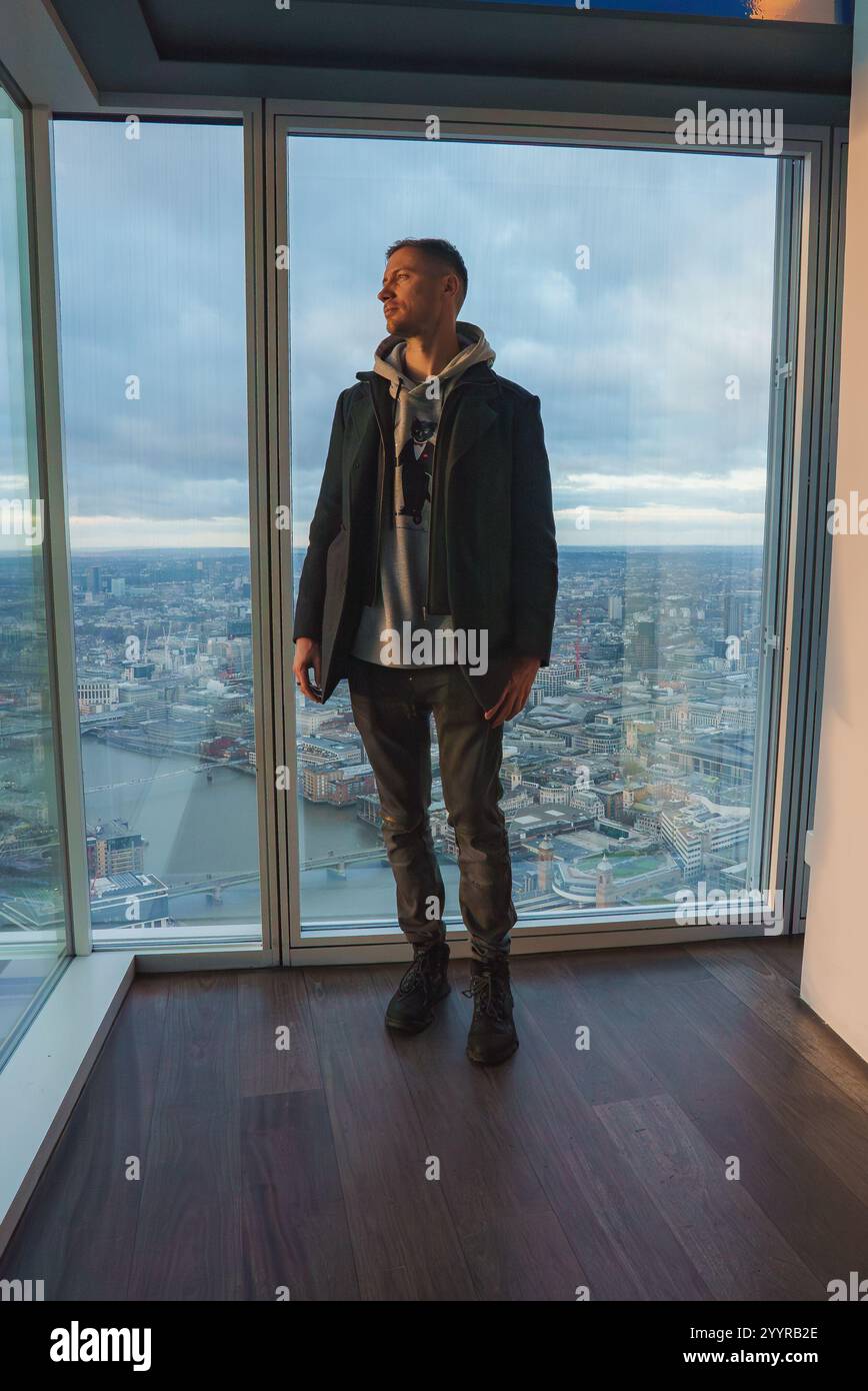 A person stands inside a modern high rise with dark wooden floors ...
