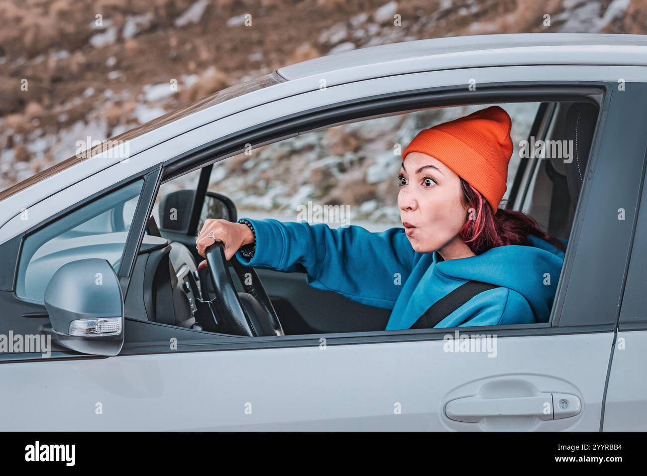 Surprised young woman driving car, emotion and caution on a road ...