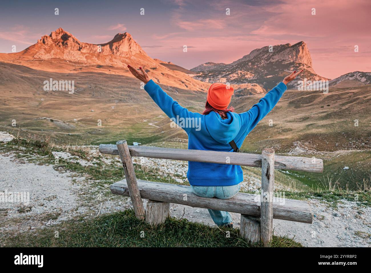 Female tourist sitting on wooden bench with arms raised, enjoying a ...