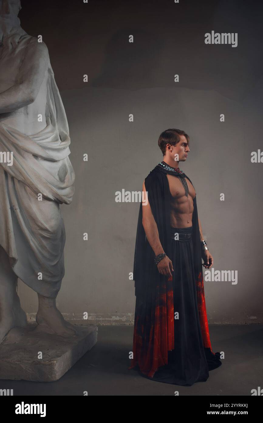 Muscular charismatic bodybuilder model in a silk cape makes an ...