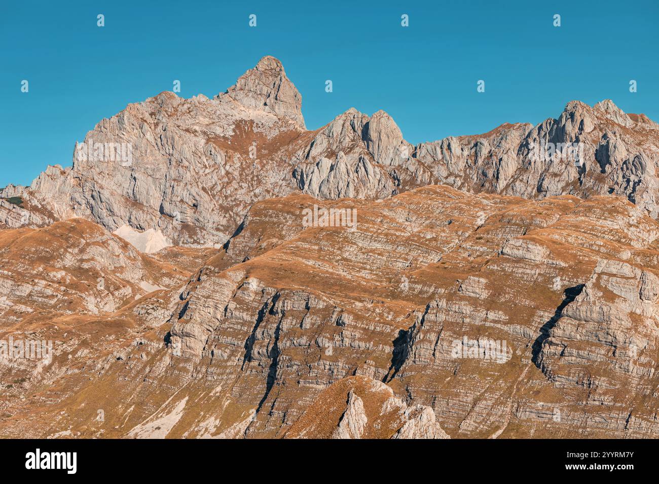 Impressive mountain range with rocky peaks under a vibrant blue sky ...