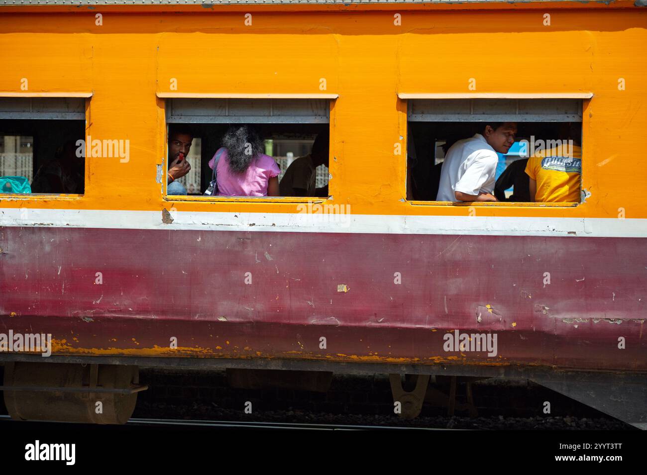 Colorful train with passengers visible through open windows, showcasing ...