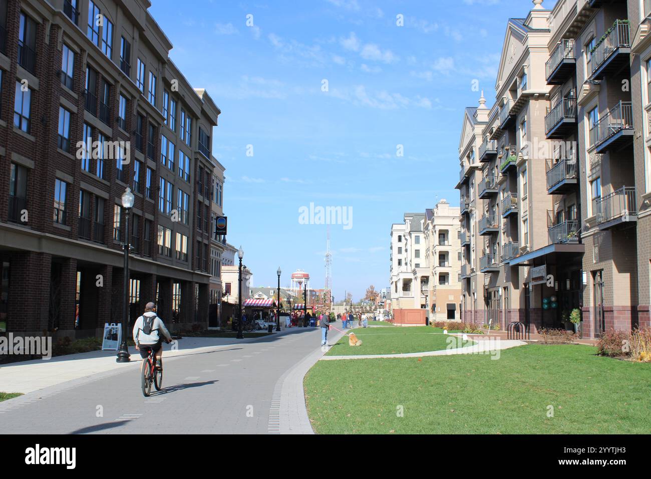 Man riding a bicycle on the Monon Greenway Path between apartment buildings in Carmel, Indiana ...