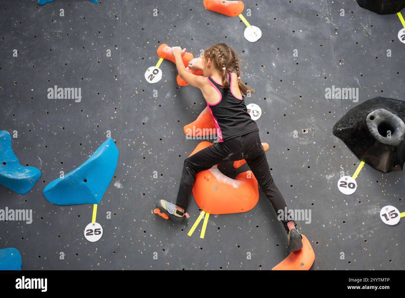 Courageous girl climbing artificial rock wall at bouldering gym. Low ...