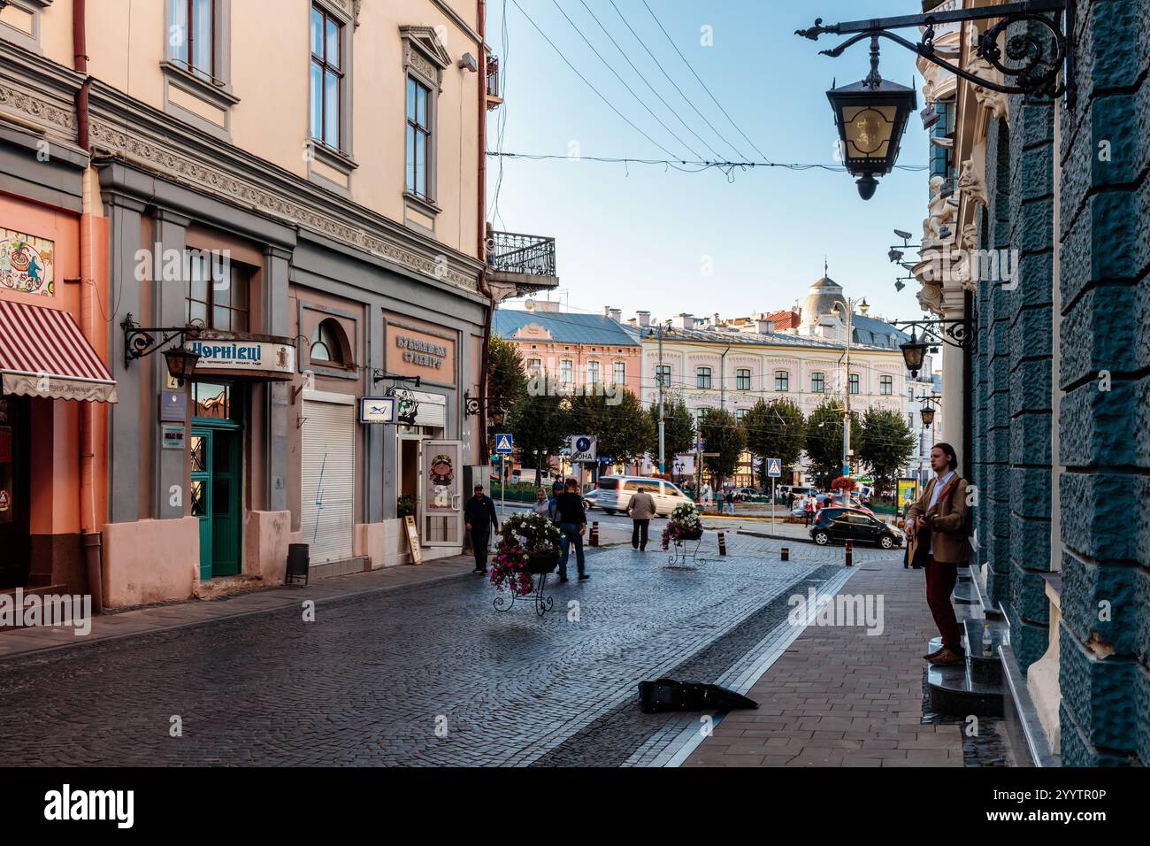 A street scene with a man standing on the sidewalk. There are several ...