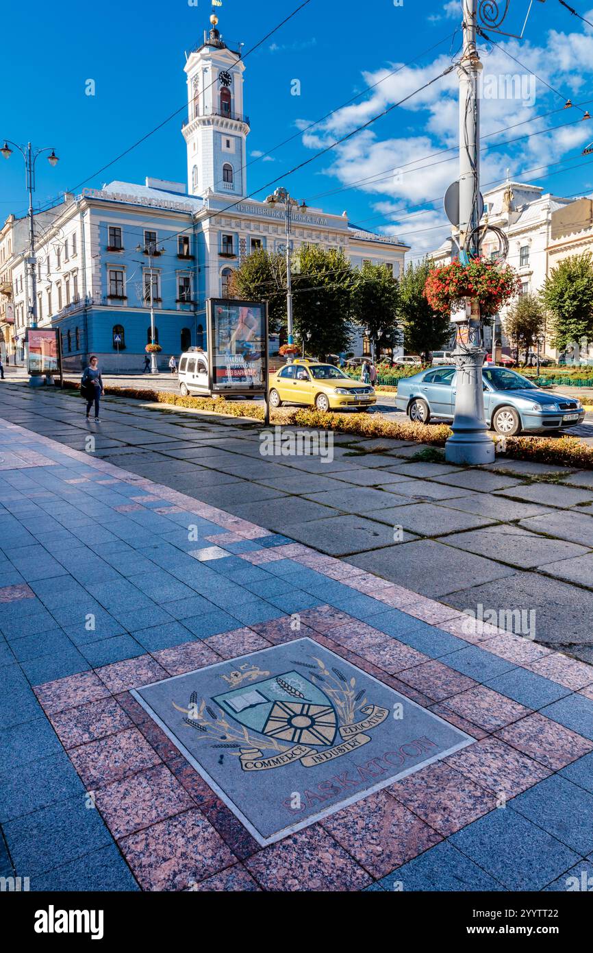 A stone with a coat of arms on it is on a sidewalk. The coat of arms is ...