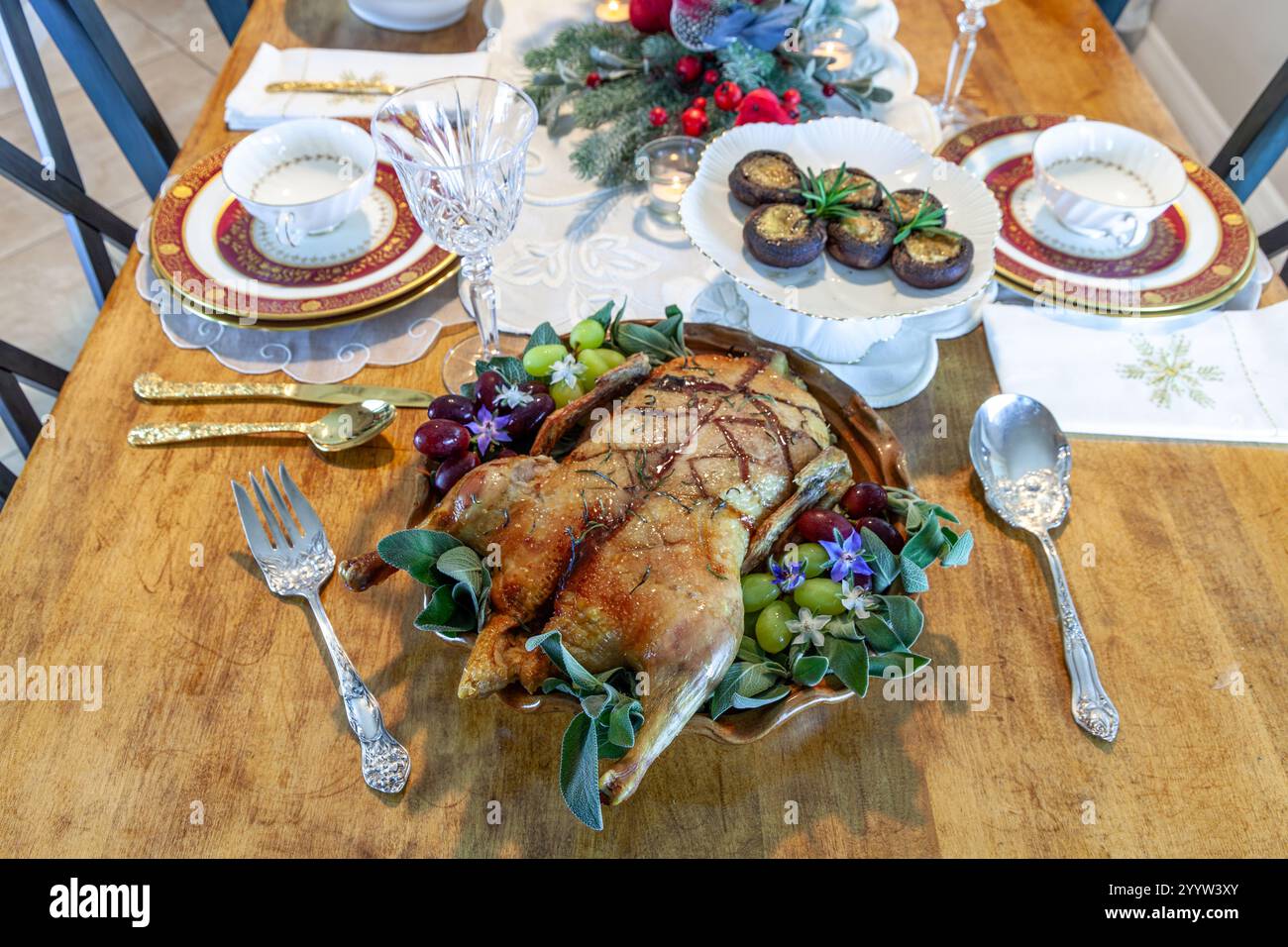 Roasted duck on a platter with sage leaves and grapes on a formal table ...