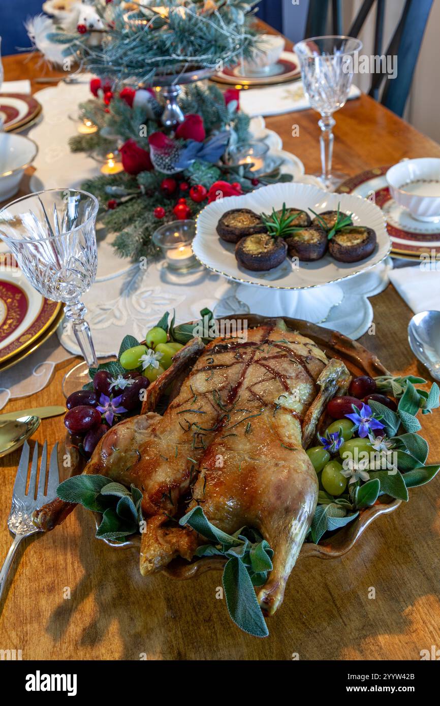 Roasted duck on a platter with sage leaves and grapes on a formal table ...