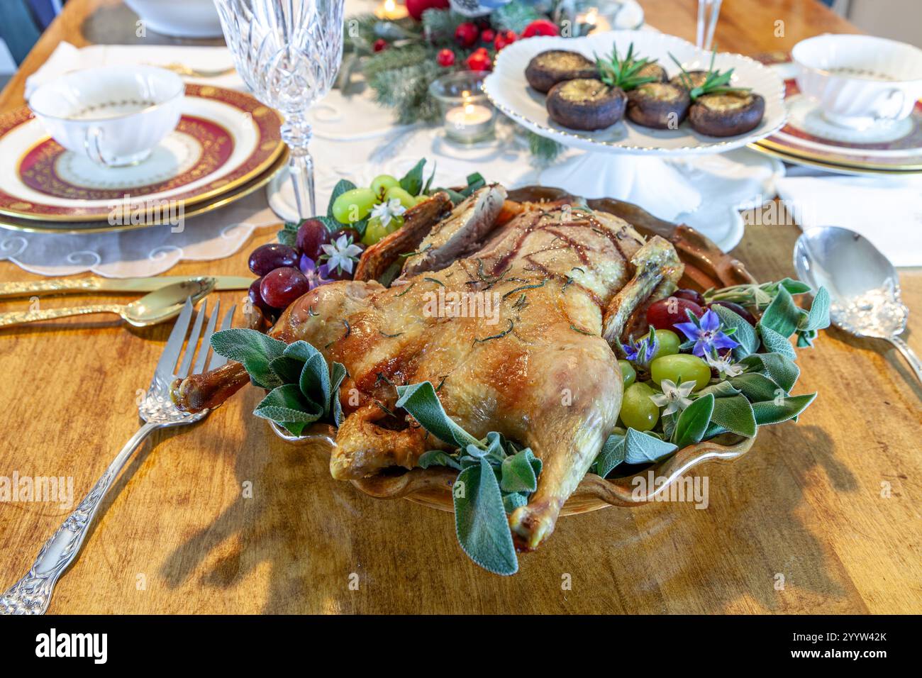 Roasted duck on a platter with sage leaves and grapes on a formal table ...
