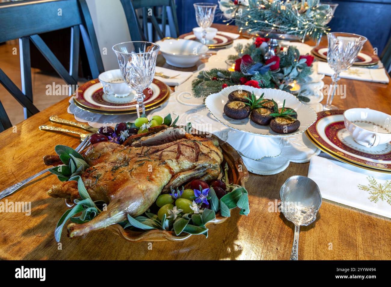 Roasted duck on a platter with sage leaves and grapes on a formal table ...