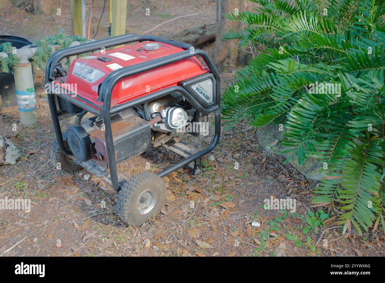 Portable red and black electric generator on left edge of a dirt trail ...