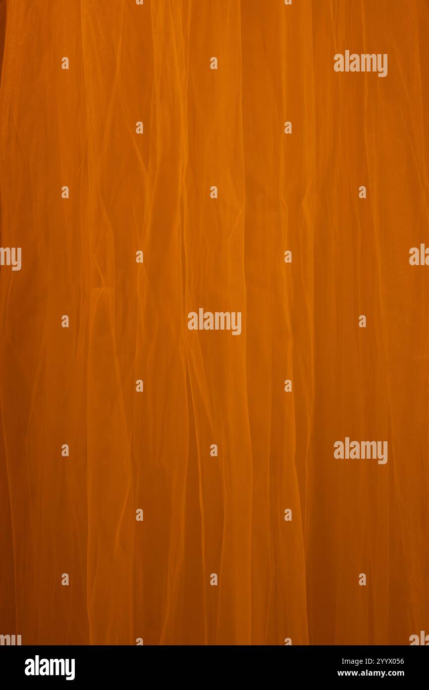 A curtain of sheer orange fabric creates an elegant and soft visual ...