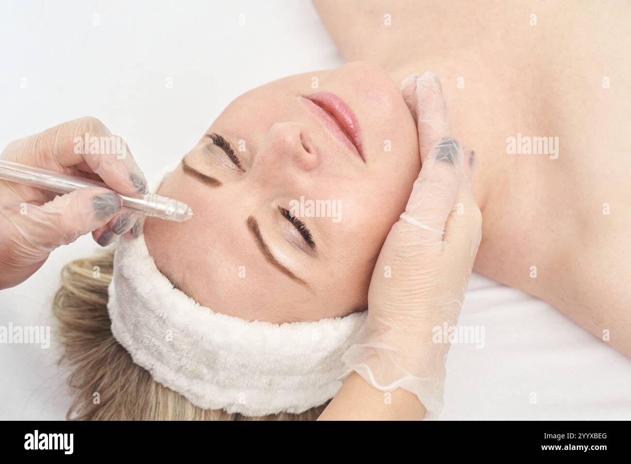 Mature caucasian female receiving cosmetic injection in forehead for ...