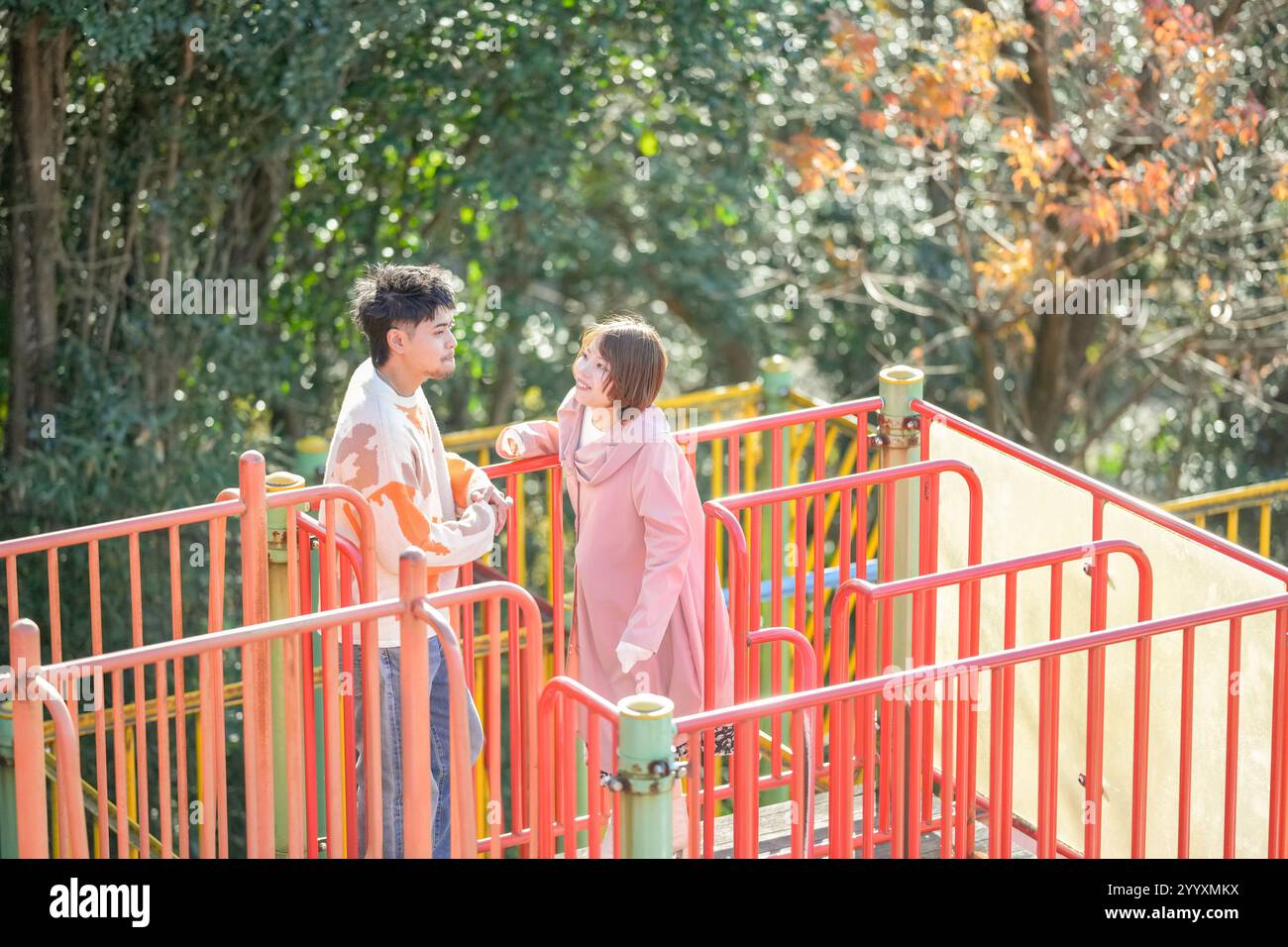 Couple in their 20s are having fun playing on playground equipment in ...