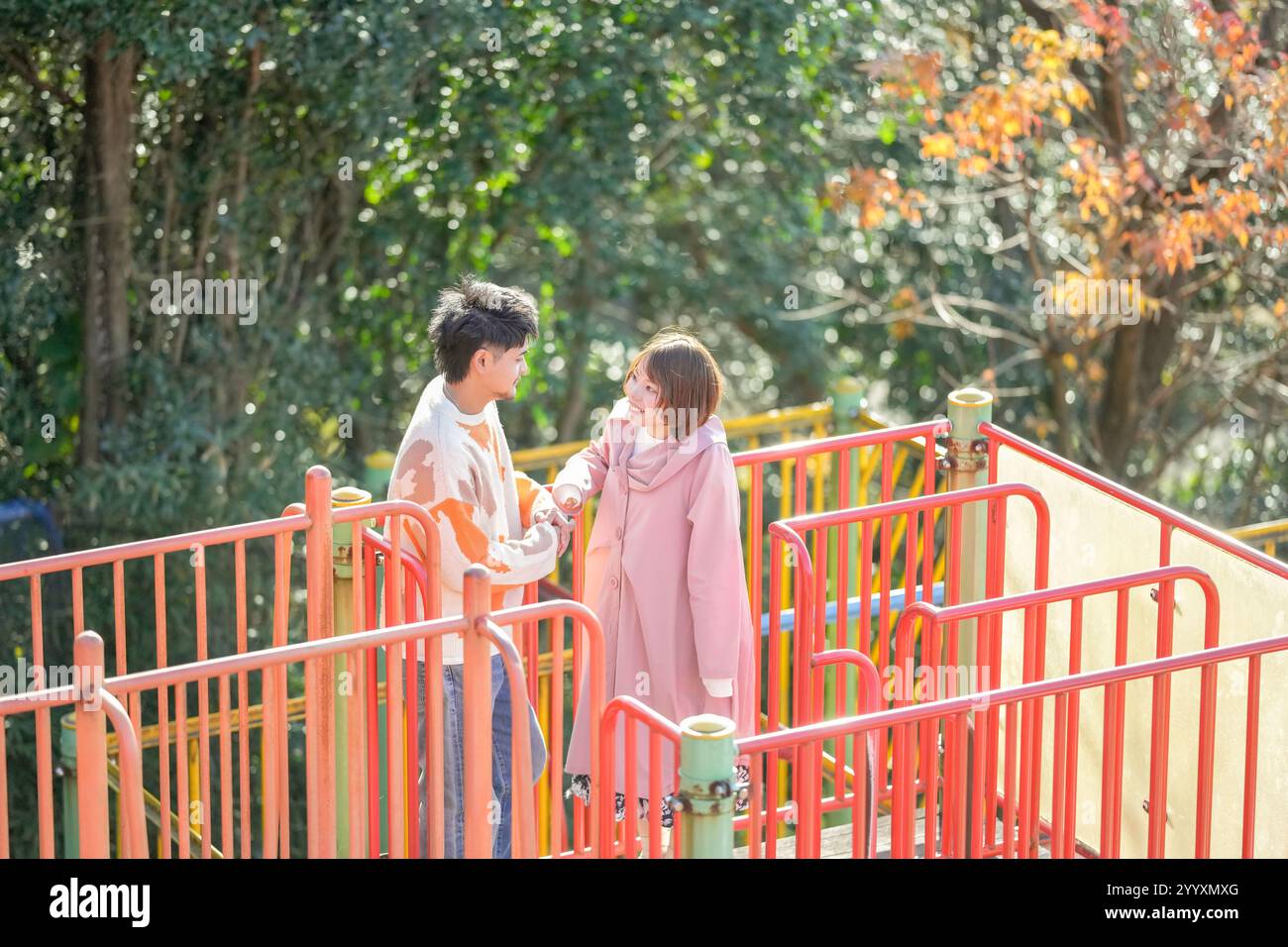 Couple in their 20s are having fun playing on playground equipment in ...