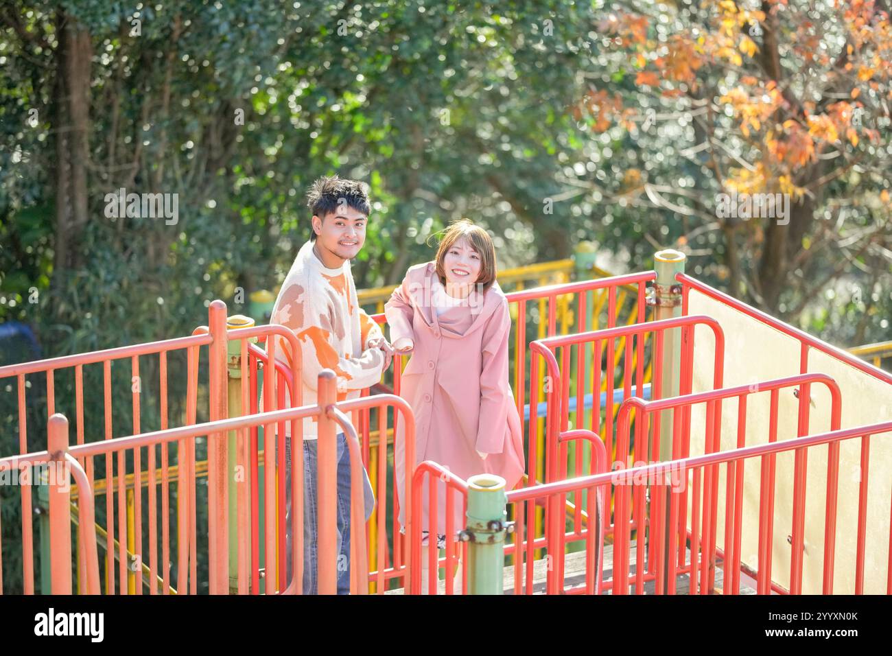 Couple in their 20s are having fun playing on playground equipment in ...