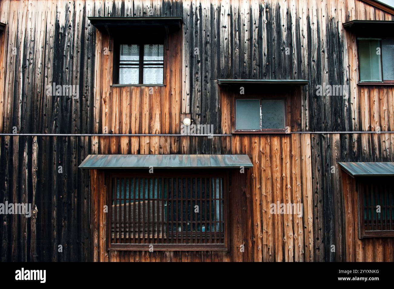 A pattern of windows on a weathered façade of an old wooden Japanese ...
