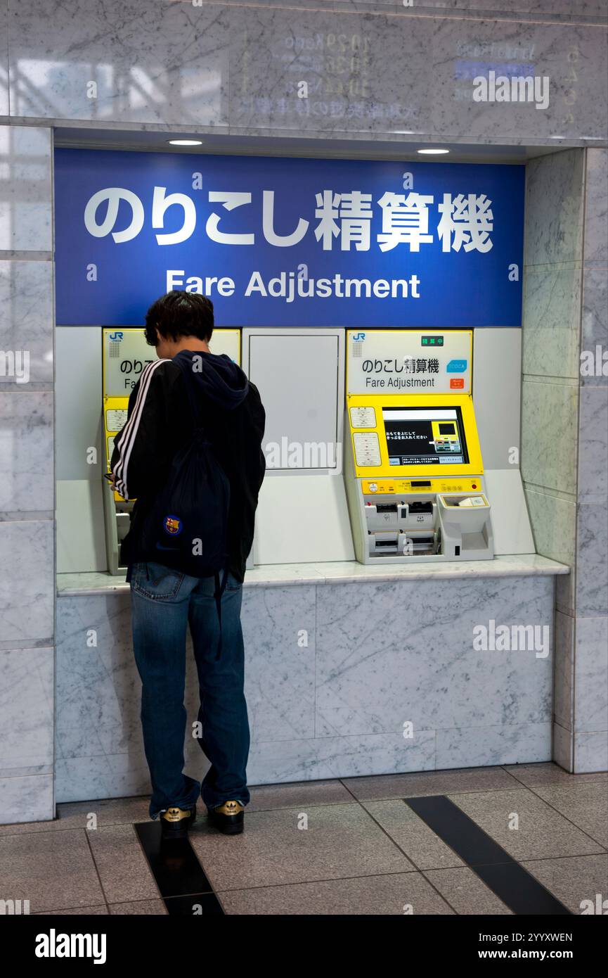 Passenger adjusting his train ticket fare at a vending machine inside ...