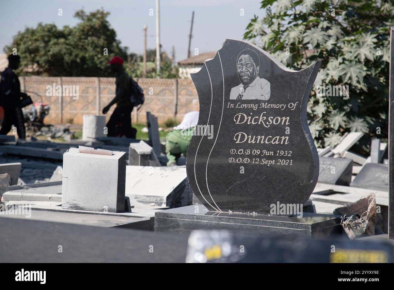 People walk past tombstones at a cemetory in Harare, Zimbabwe ...