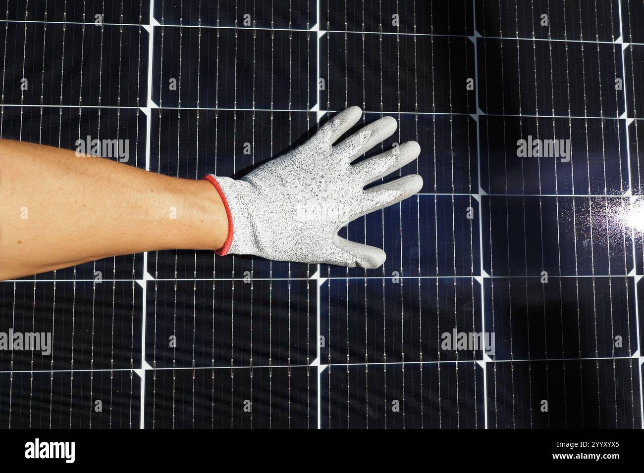 Close-up. Hand touching solar panel cells while wearing a protective ...