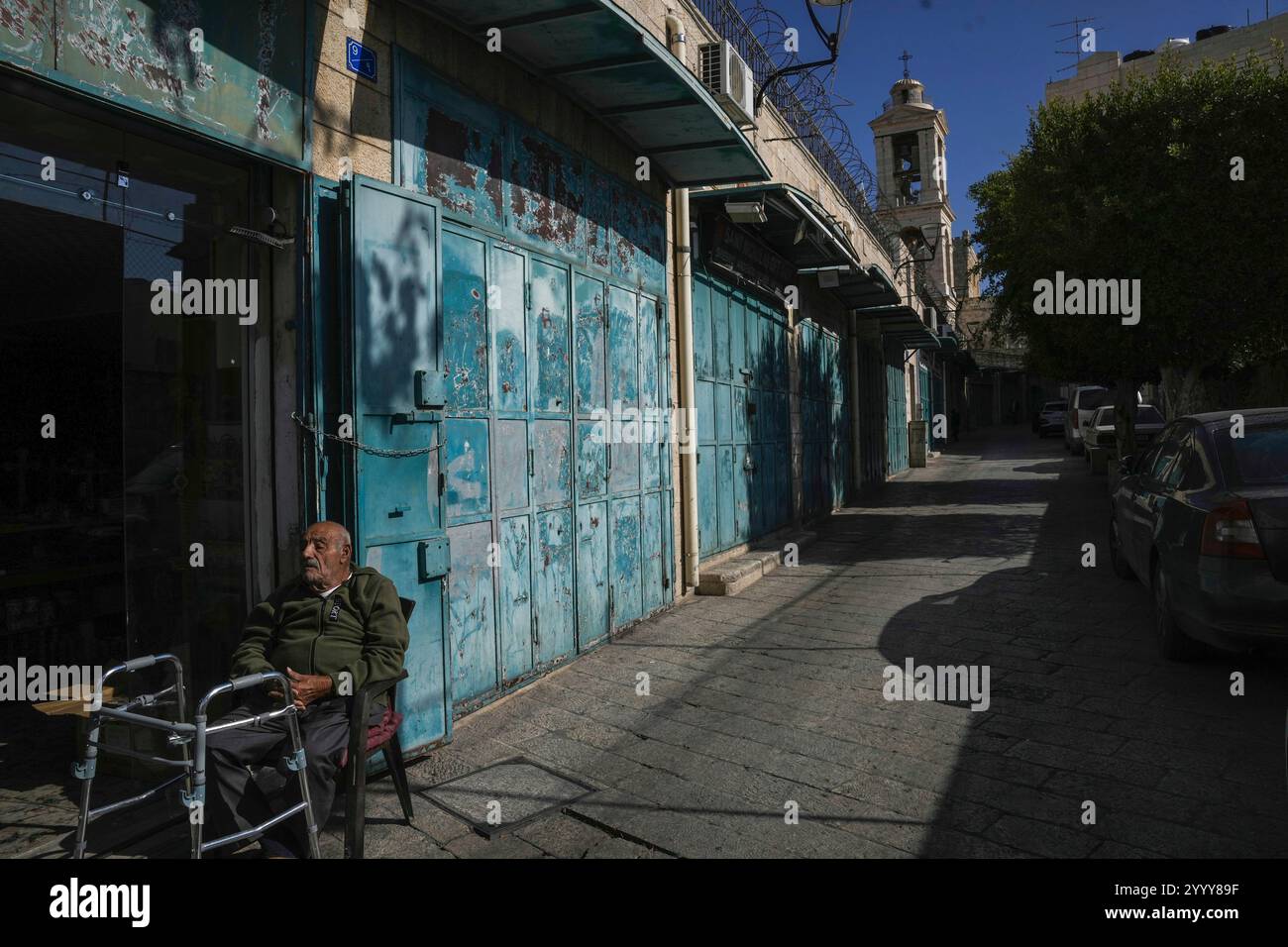 A man rests by a row of empty shops near the Church of the Nativity ...