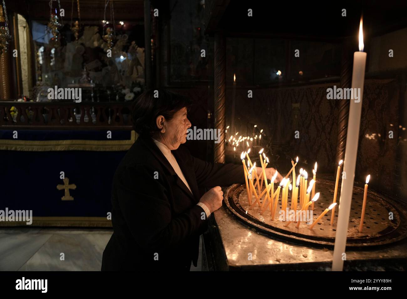 A worshipper lights a candle in the Church of the Nativity, where ...