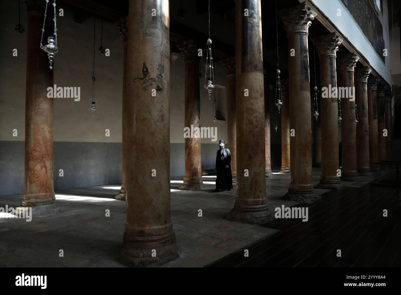 A priest walks in the Church of the Nativity, where Christians believe ...