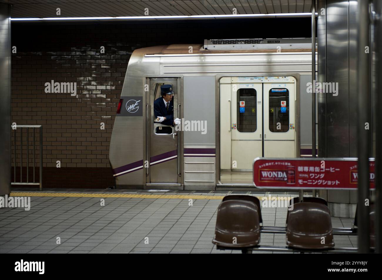 An Osaka subway train conductor looks out a window the rear carriage to ...
