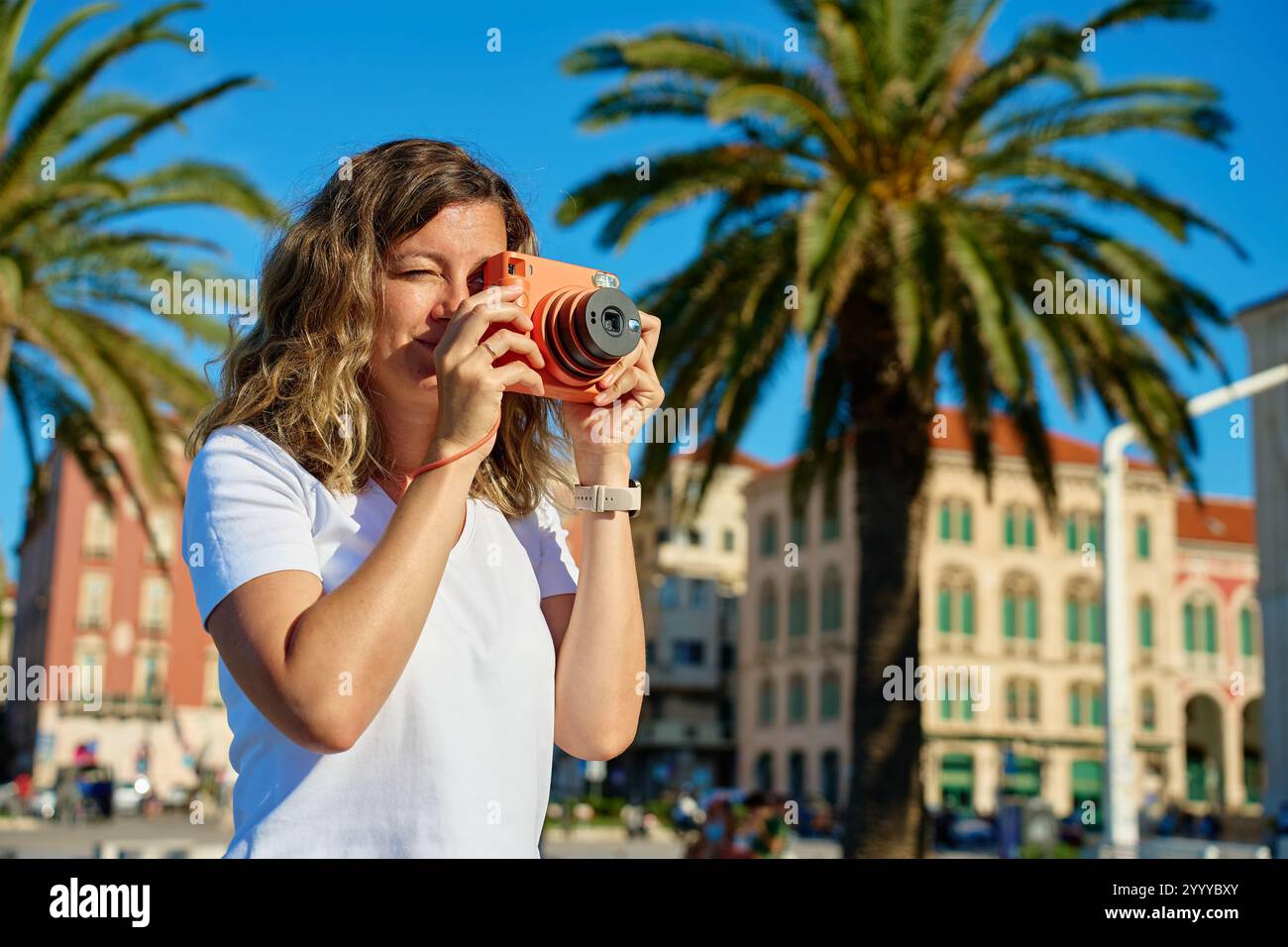 Female traveler in casual clothing taking picture in coastal town ...