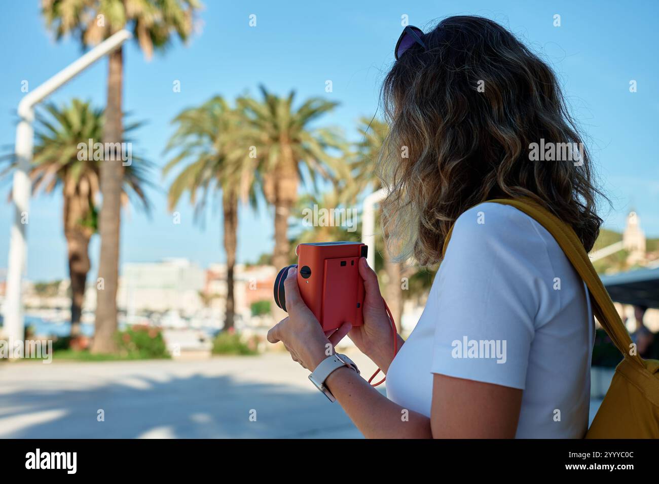 Female traveler in casual clothing taking picture in coastal town ...