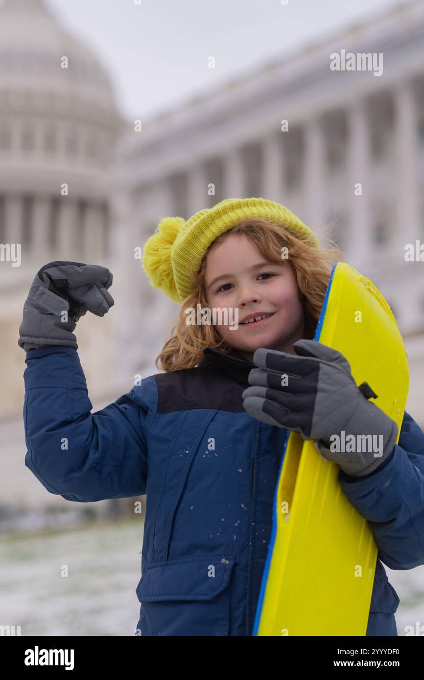 Kid play with snowboard in winter park. Winter kids with first snow ...