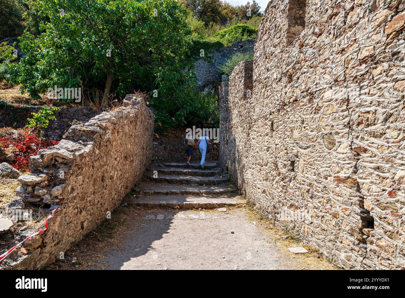 Two visitors walking along the historic stone pathways of Mystras ...
