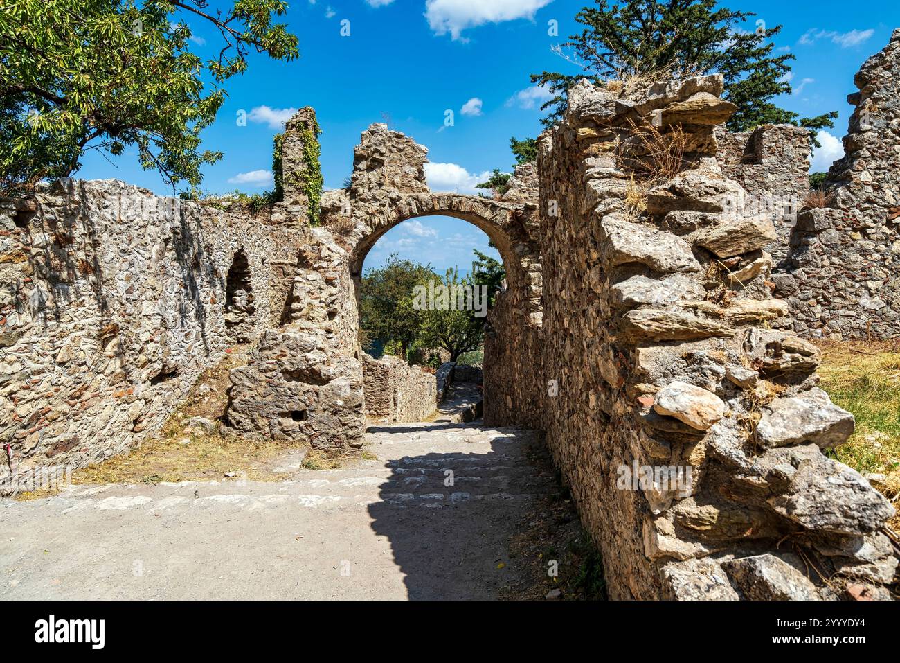 A historic stone archway in the ruins of Mystras, Greece, surrounded by ...