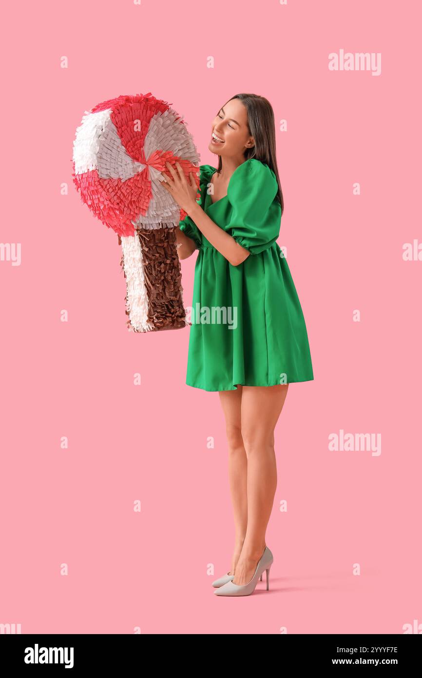 Beautiful woman with candy pinata on pink background Stock Photo - Alamy
