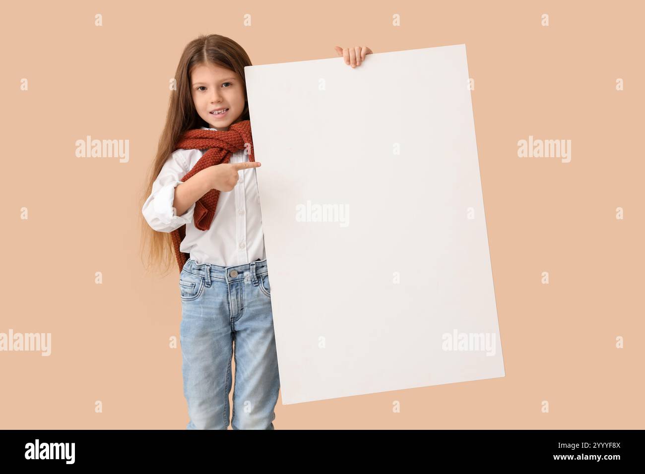 Cute little girl pointing at blank poster on beige background. Opposite ...