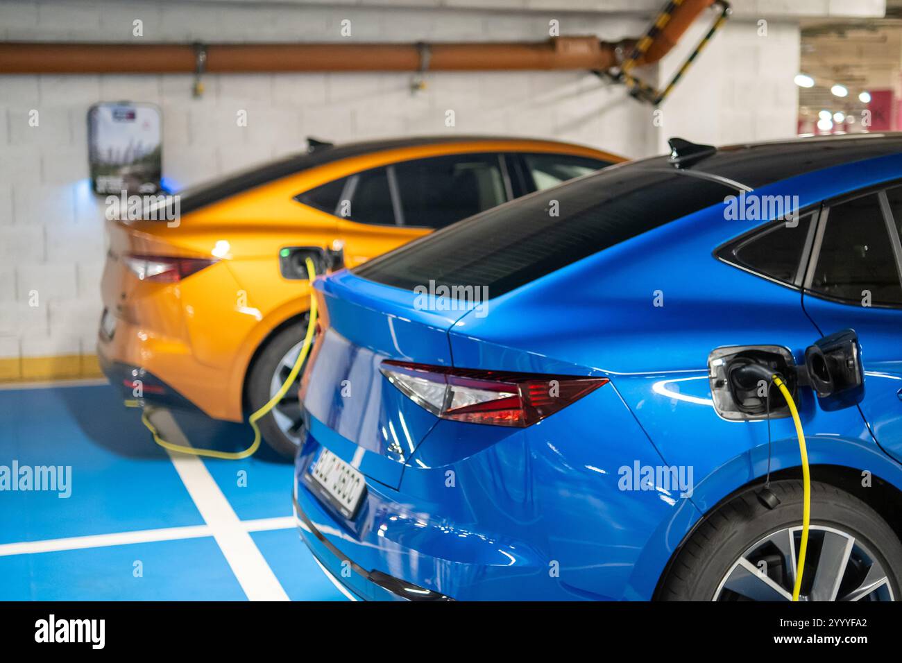 Electric vehicles blue and orange charging in a modern parking garage ...