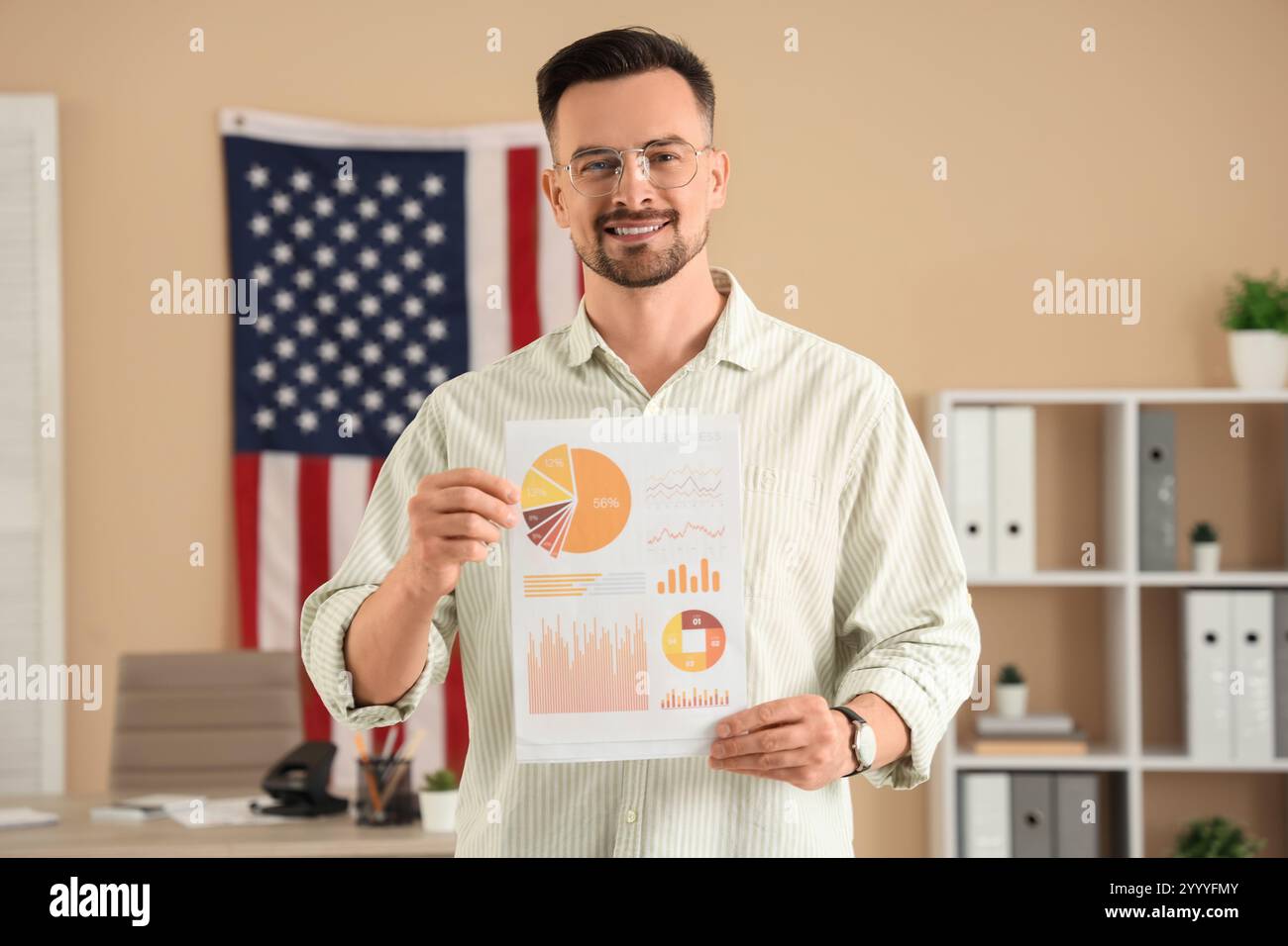 Handsome young happy man with diagrams and flag of USA in office Stock ...