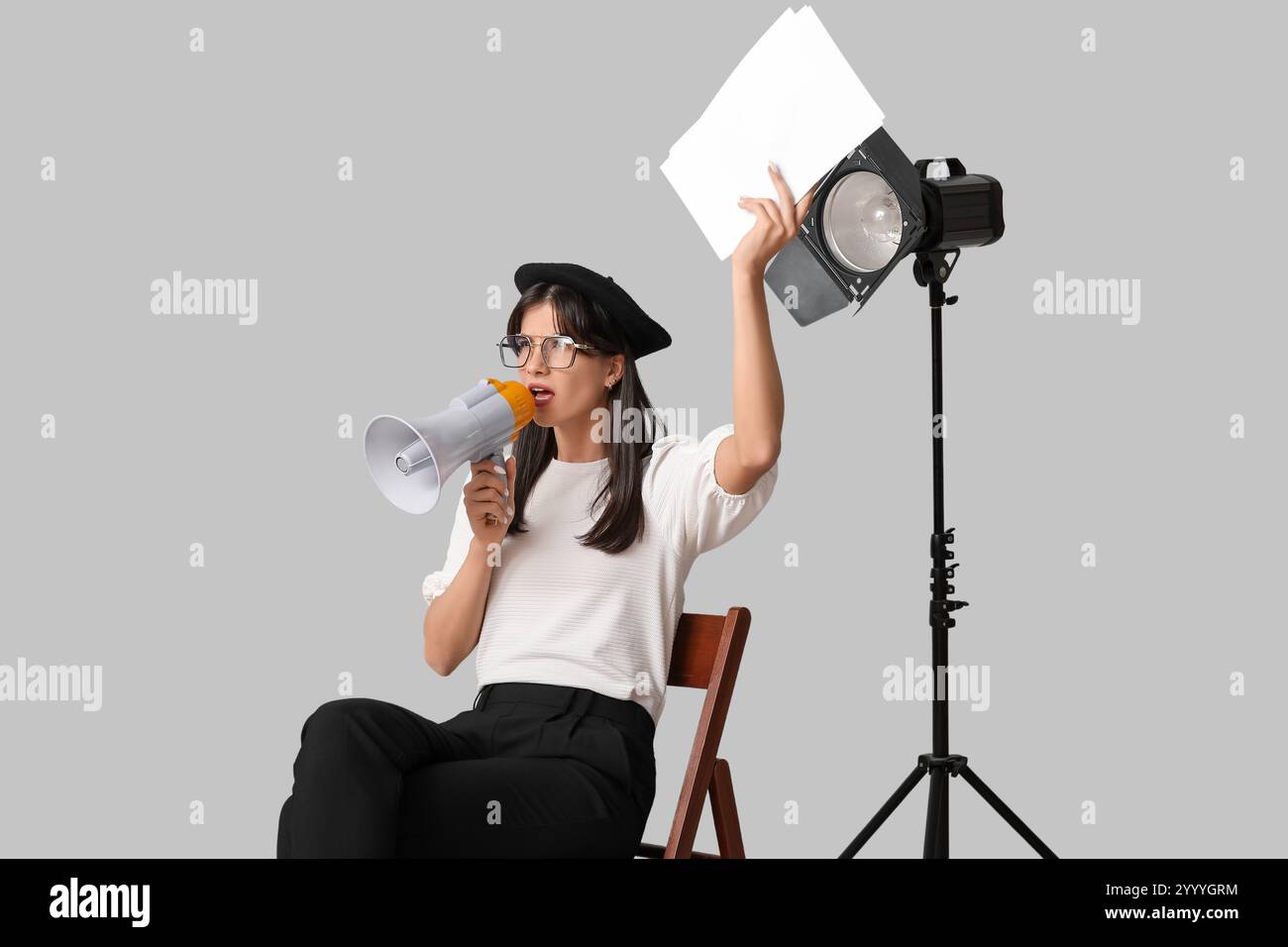 Young displeased female film director with megaphone, script and studio ...