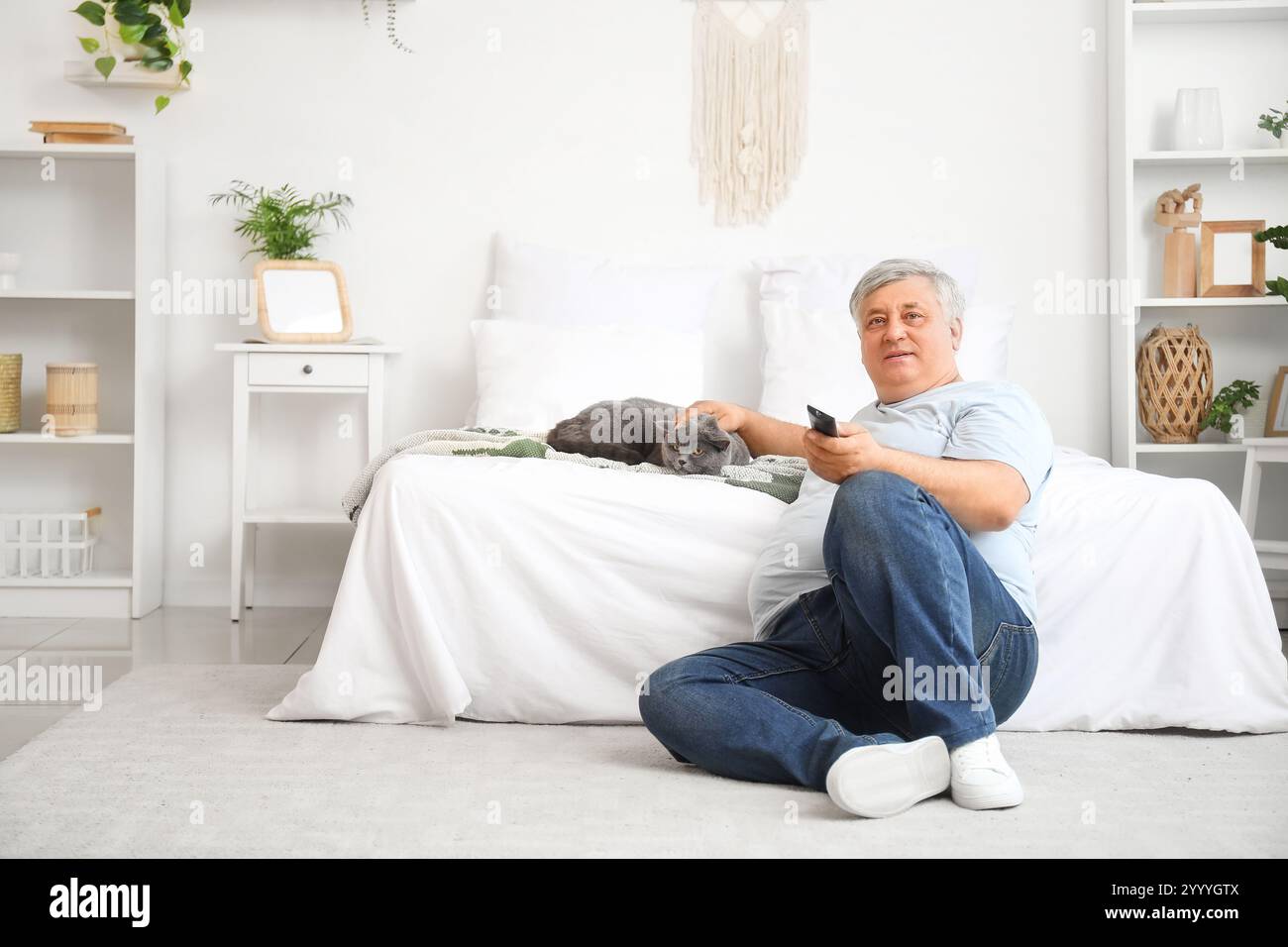 Senior man with cute cat watching TV in bedroom Stock Photo - Alamy