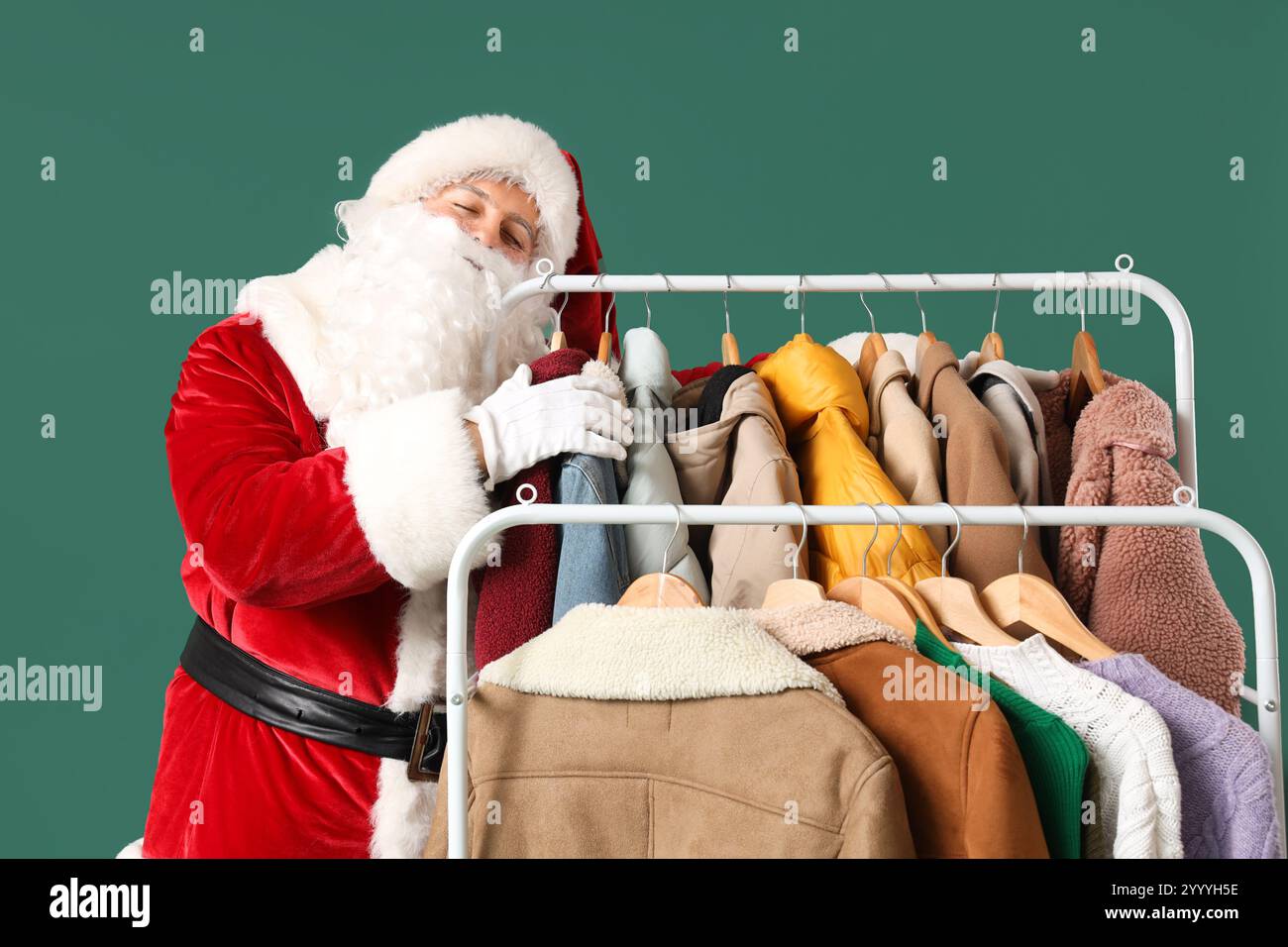 Santa Claus and rack with different clothes on green background Stock ...